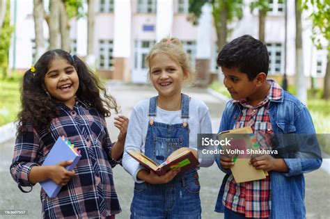 학교로 돌아갑니다 배낭을 들고 학교 앞에서 포옹하고 웃으며 세 친구를 가까이에 두세요 학교 마당에서 재미를 갖는 학교 아이들의