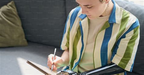 거실의 소파에 앉아 연필로 스케치를 그리는 동안 메모장을 들고 있는 젊은 여자 사진 Unsplash의 사람 이미지