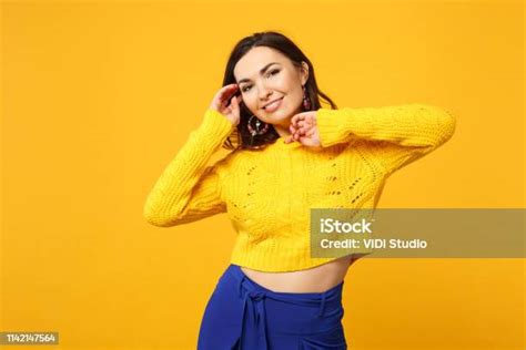 스웨터에 즐거운 젊은 여자의 초상화 파란색 바지 카메라를 찾고 노란 오렌지 배경에 고립 된 얼굴 가까이 손을 유지 사람들은 진심으로 감정 라이프 스타일 개념입니다 복사