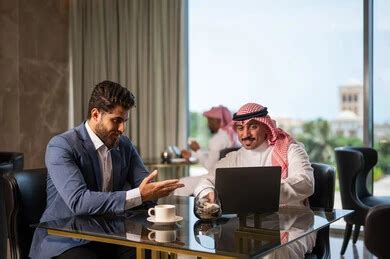رجل أعمال عربي سعودي خليجي يرتدي الزي السعودي مع رجل أعمال عربي يرتدي