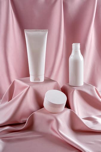 파스텔 섬유 배경과 연단에 있는 세 개의 흰색 병 화장품 미용 제품 개념입니다 파스텔 핑크 큐브 연단은 화장품을 보여줍니다 0명에 대한 스톡 사진 및 기타 이미지 Istock