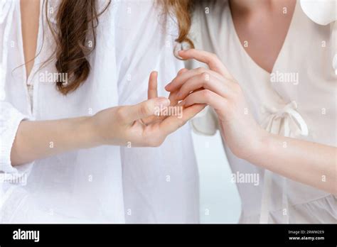 Two Girls Dressed In White Touch Each Others Hand Part Of Body