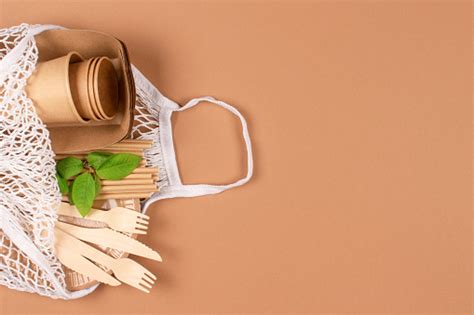 Kraft 종이 음식 컵과 복사 공간이있는 밝은 갈색 배경에 흰색 면화 그물 가방에 나무 칼 붙이가있는 용기 환경 친화적 인