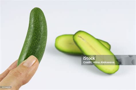 흰색으로 분리된 뒷면에 얇게 썬 칵테일 아보카도가 있는 미니 아보카도를 들고 있는 손을 닫습니다 건강한 삶을 위해 특별히 재배 된 이국적인 녹색 완전 채식 식품 기능성 식품