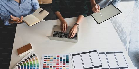 그래픽 디자인 팀이 함께 작업하고 스마트폰의 새로운 기능에 대해 브레인스토밍하는 상위 뷰 이미지입니다 협업공동 작업자회의함께 일하는 개념 사진 Unsplash의