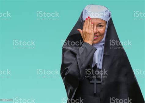 격리 된 배경 얼굴과 놀라운 감정에 확신 미소와 함께 손으로 한쪽 눈을 덮고 위에 중 년 수석 기독교 가톨릭 수녀 여자 가리기에