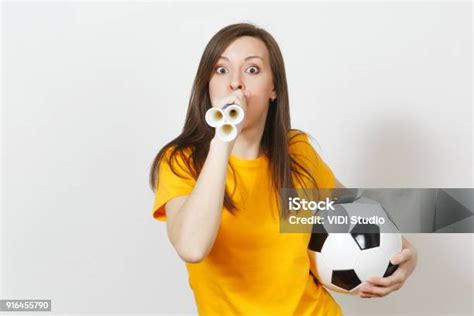 아름 다운 유럽 젊은 쾌활 한 행복 한 여자 축구 팬 또는 노란색 유니폼에 선수 보유 하 고 불면 축구 파이프 흰색 배경에 고립 된 공 스포츠 축구 건강 한 라이프 스타일