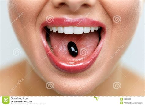 Красивый рот женщины с пилюлькой на языке принимать микстуры девушки Стоковое Изображение