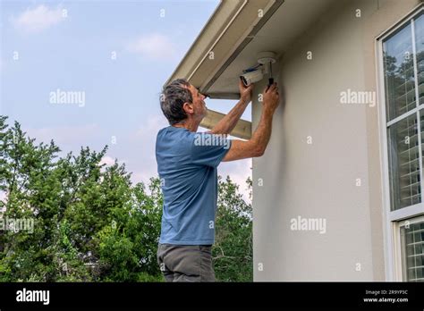 White Caucasian Man Person Installing Repairing A Security Camera Under