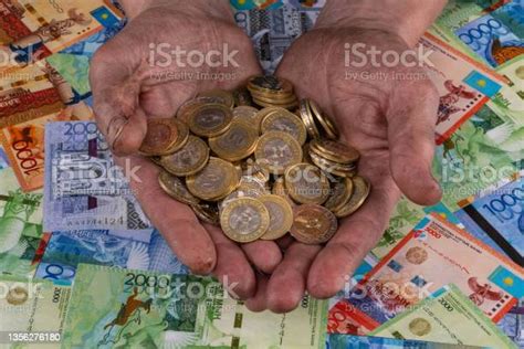 카자흐스탄 지폐의 배경에 대해 100 및 200 텐지의 교단에 동전의 무리를 들고 일하는 남자의 남성 손 Brand Name Mobile Payment에 대한 스톡 사진 및