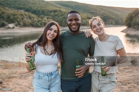 세 명의 다인종 가장 친한 친구가 맥주병을 들고 호숫가에 서서 카메라를 직접 바라보는 초상화 남성에 대한 스톡 사진 및 기타 이미지 Istock