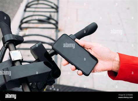 Hand Of Female Professional Scanning QR Code On Electric Push Scooter From Smart Phone Stock