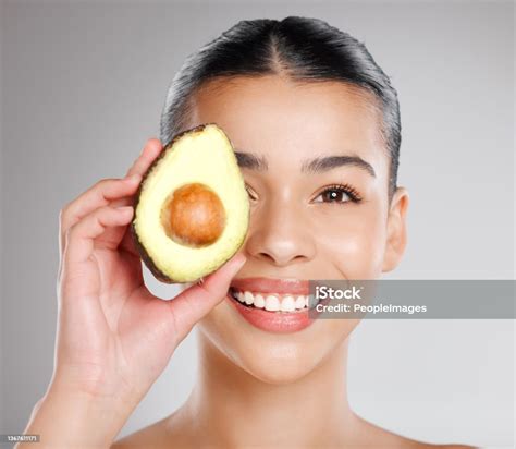 회색 배경에 대한 그녀의 얼굴에 아보카도를 들고 매력적인 젊은 여자의 스튜디오 샷 아보카도에 대한 스톡 사진 및 기타 이미지 아보카도 패션모델 18 19세 Istock