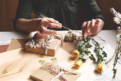 여자는 제로 폐기물 플라스틱 무료 트렌디 한 손으로 만든 선물 패키지를 공예 재활용 종이와 린넨 식탁보와 테이블에 말린 꽃 천연 에스테틱 가을에 대한 스톡 사진 및 기타