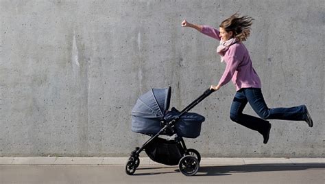 회색 콘크리트 벽 배경에 신생아 유모차와 함께 비행 슈퍼 여주인공 어머니 슈퍼 히어로처럼 보이는 아기 마차와 강한 강력한 여자 아기에 대한 스톡 사진 및 기타 이미지