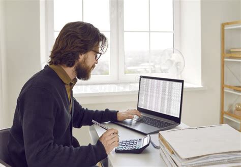 Serious Man In Office Working With Databases Using Laptop And Excel