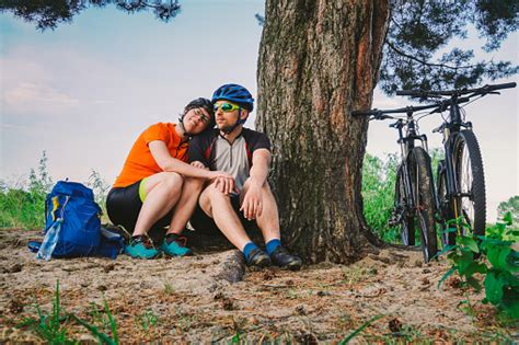 산악 자전거와 함께 행복 한 부부는 야외 레저 자연을 포용 앉아 있다 행복 한 부부 활동적인 라이프 스타일을 리드 나무 근처 숲에서 중단 휴식을 취할 테마 스포츠와 활동적인