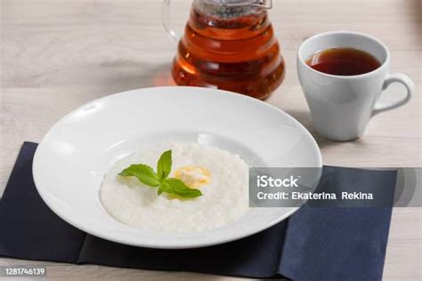 버터와 민트 잎이 있는 흰색 접시에 쌀 우유 죽이 차 한 잔을 들고 나무 배경에 놓습니다 건강한 아침 식사 적절한 아침 버터에 대한 스톡 사진 및 기타 이미지 Istock