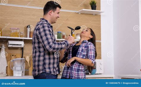 Marido Joven Y Esposa Que Luchan Con Las Herramientas De La Cocina Y Que Se Divierten Imagen De