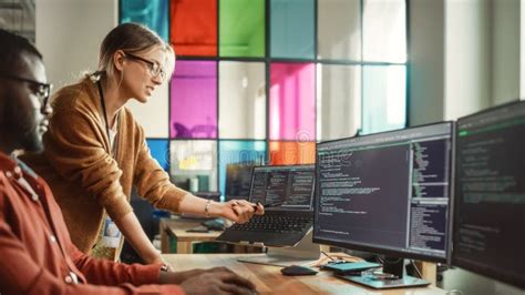 Black Programmer Shows Code On Desktop Computer To Female Start Up Founder In Creative Office