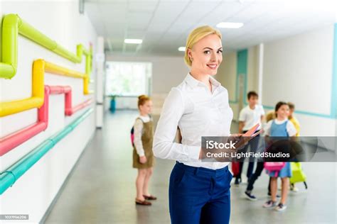 배경에서 아이 들과 함께 학교 복도에 서 서 아름 다운 미소 선생님 고등학교 이하에 대한 스톡 사진 및 기타 이미지 고등학교