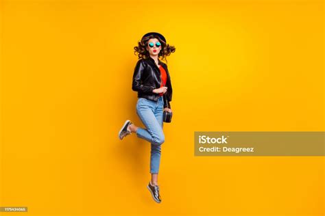 귀여운 매력적인 소녀 점프의 전체 길이 사진은 그녀의 여행에 공기 키스를 보내 남자는 노란색 색상 배경을 통해 고립 된 검은 가죽 재킷 데님 청바지를 착용 유치 가방에 대한