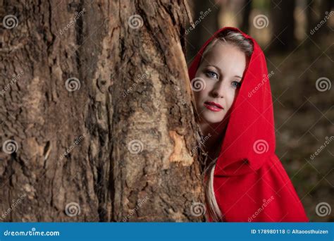 Attractive Woman Dressed A Little Red Riding Hood Hide Behind A Tree In
