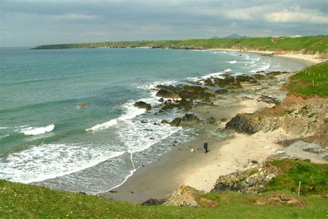 A Person Walking On The Beach Next To The Ocean With Waves Coming In