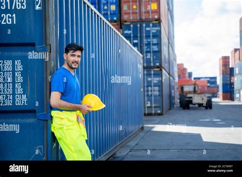portrait of container worker leaning on cargo container and looking up