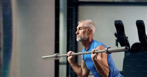 체육관에서 근력 운동을 하는 동안 바벨과 함께 운동하는 성숙한 운동선수 사진 Unsplash의 생명력 이미지