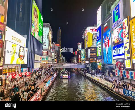 The Dotonbori River At Night With Lit Up Billboards And Neon Lights In