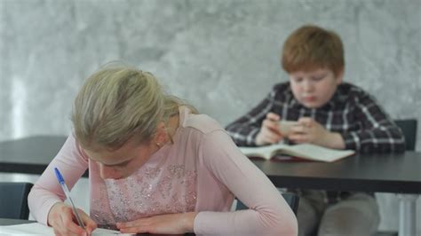 A Babe Girl In A Classroom Concentrating On Her Test While Her Classmate Playing Games Stock