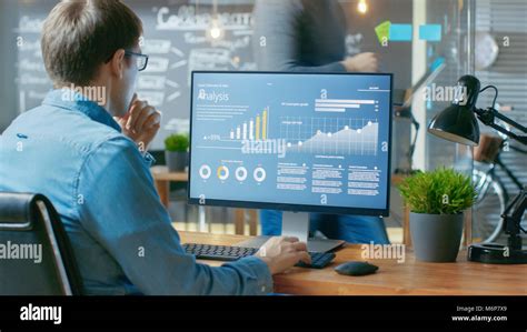 Analyst Works On A Personal Computer Showing Statistics Graphs And Charts In The Background