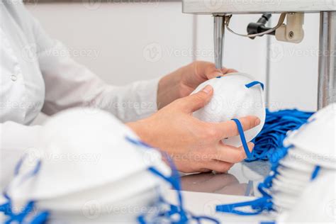 A Woman Works At A Machine For The Manufacture Of Medical Masks With
