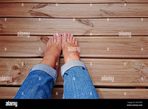 Pov View Of Womans Barefoot Legs Wearing Blue Jeans On Wooden Floor
