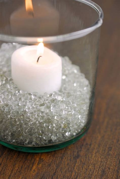 Having A Small White Votive In A Wide Cylinder Vase Nestled In Some