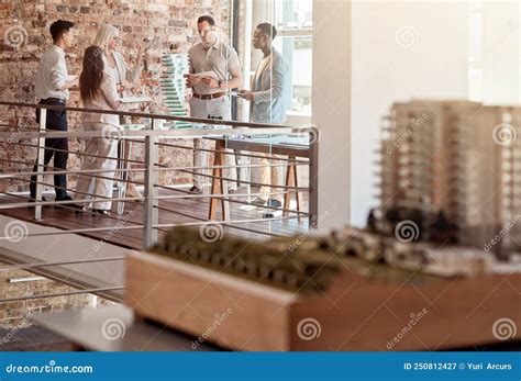 Group Of Diverse Architects Discussing Plans Blueprints And Schematics During A Meeting In