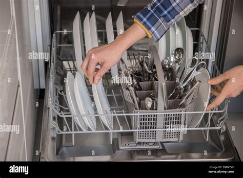 Dishwasher Open And A Person Removing The Washed Dishes Concept Of