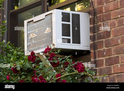 Exterior View Of Air Conditioning Window Unit Extruding From The Window Sill Of A Red Brick