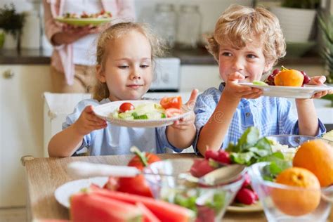 Siblings Holding Salad Plates In Kitchen At Home Stock Image Image Of