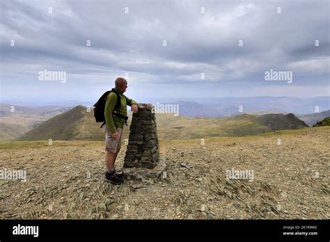 Walker At The Summit Cairn Of Helvellyn Fell Lake District National