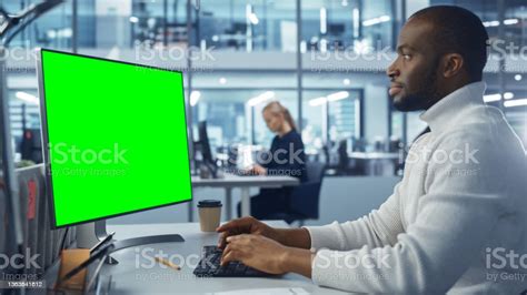 다양한 현대 사무실 녹색 화면 모의 디스플레이와 데스크톱 컴퓨터를 사용하여 잘 생긴 흑인 사업가 전자 상거래 앱 개발 프로젝트 마케팅 빅 데이터 분석 담당 매니저 20 24