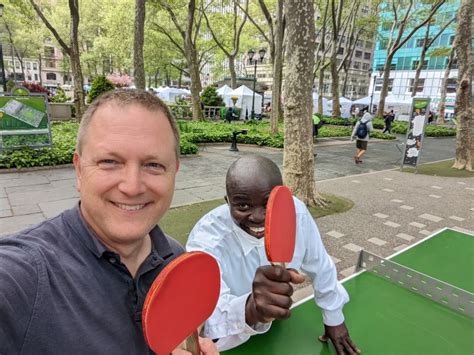 an attendant with paddles and balls sits next to two ping pong tables