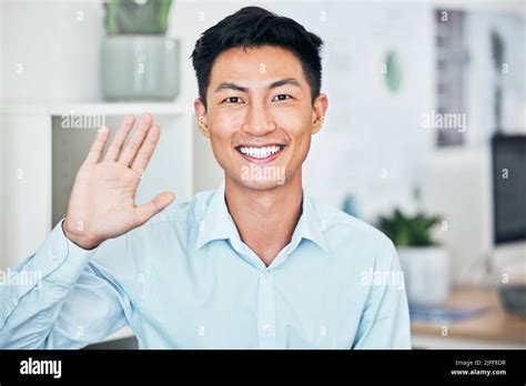 Happy Business Man Greeting Waving And Saying Hello With Hand Gesture While Smiling And Looking