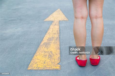 여자는 아스팔트도로에 노란색 교통 화살표 간판으로 걸어가 빨간 신발을 착용 가리키기에 대한 스톡 사진 및 기타 이미지