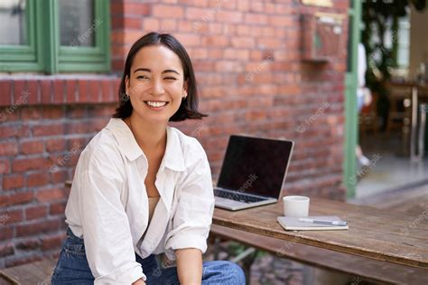 Premium Photo Beautiful Korean Girl With Laptop Sitting In Outdoor Cafe Drinking Coffee And