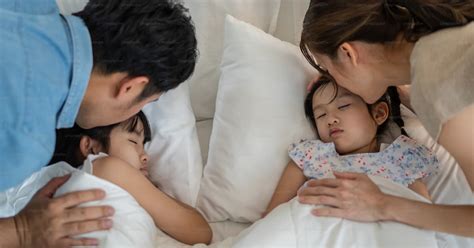 아시아의 사랑하는 부모는 집에서 침실에서 자고있는 딸을 돌 봅니다 매력적인 행복한 가족 커플 어머니와 아버지는 아침에