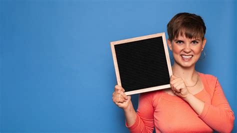 파란색 바탕에 빈 편지판을 들고 웃고 있는 젊은 여성의 스튜디오 사진 복사 공간 광고 또는 텍스트를 위한 공간 25 29세에 대한 스톡 사진 및 기타 이미지 Istock