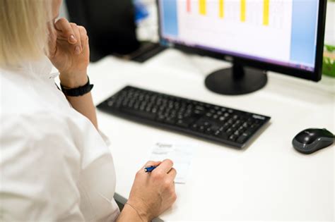 의료 진료소에서 환자를 치료하기 위해 약물을 처방하고 처방하는 흰색 의료 코트의 책상에 앉아있는 여성 의사 간호사에 대한 스톡