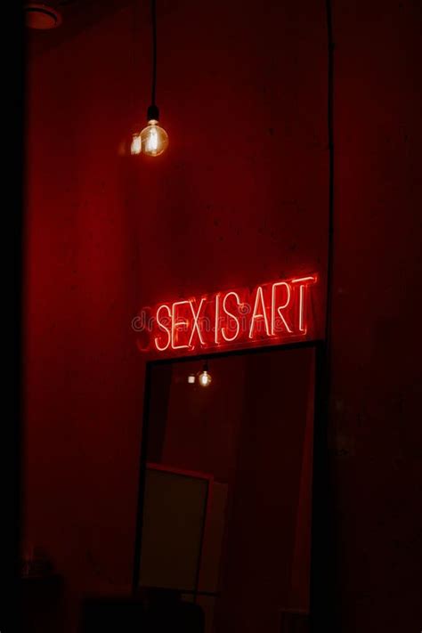 Vibrant Red Neon Sign With The Words Sex Is Art Illuminated In A Darkened Room Stock Image